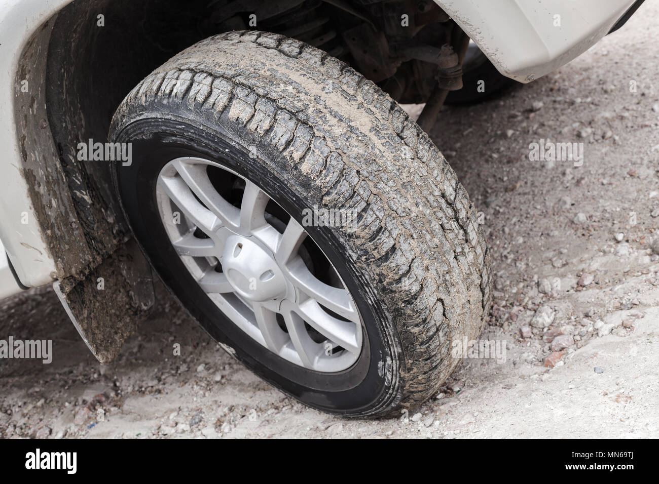 Car wheel with light alloy disc on dirty country ground, close-up photo ...