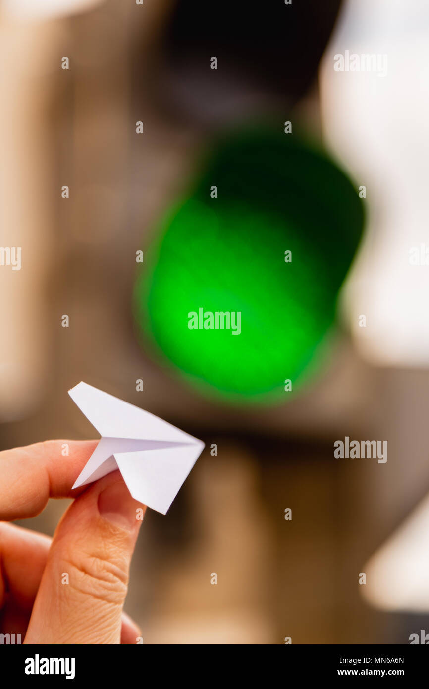 One small paper airplane in hand against a traffic light background ...
