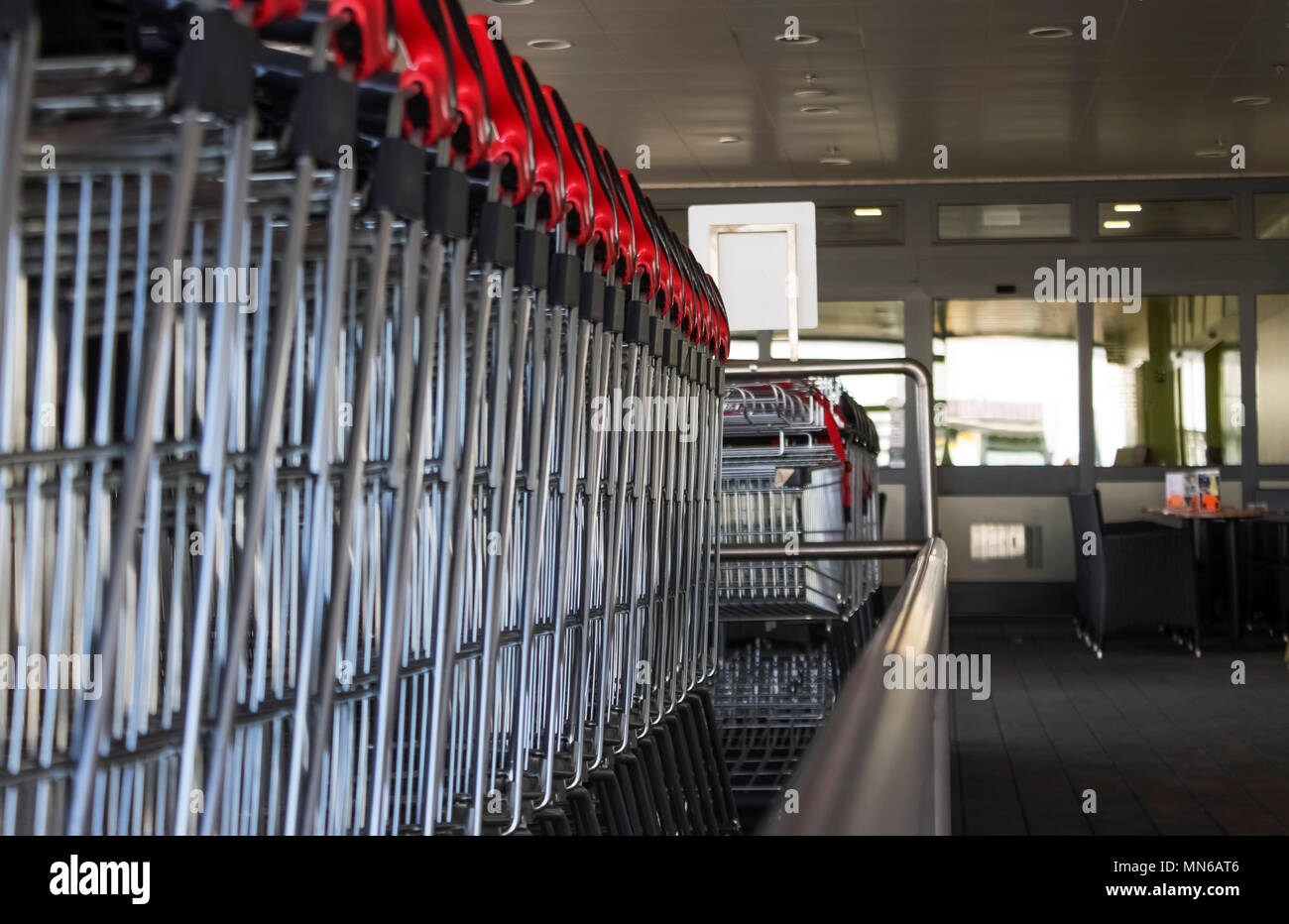 Many shopping carts in a row with red handle in front of supermarket ...