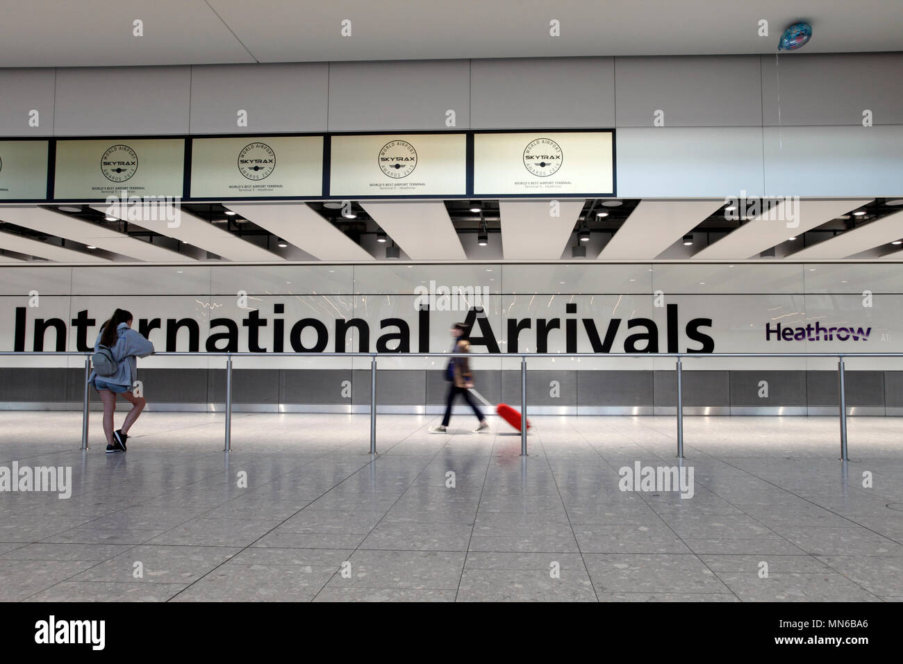 Heathrow arrivals lounge, one person arriving and one waiting Stock ...