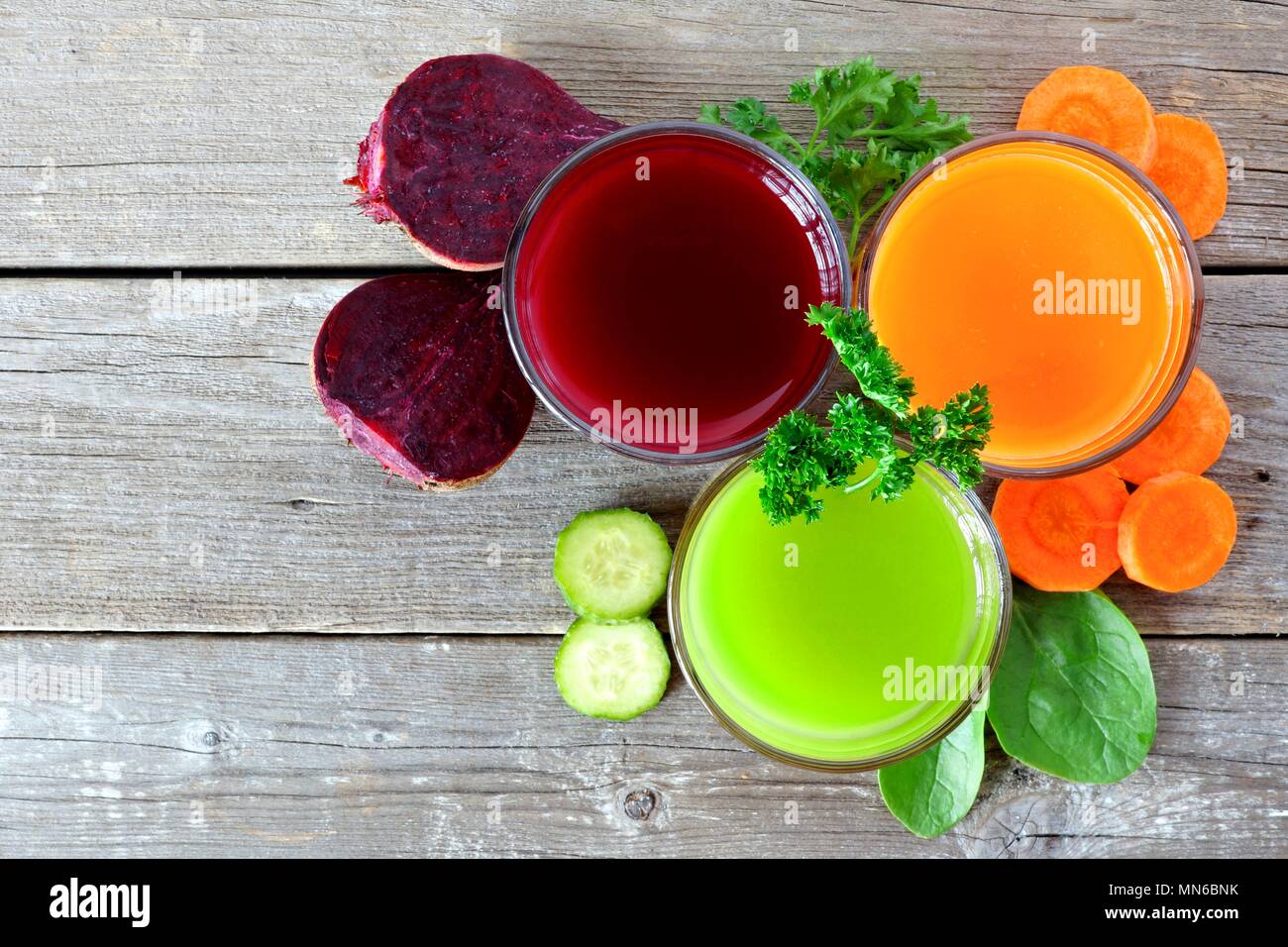Three glasses of healthy vegetable juice with surrounding ingredients ...