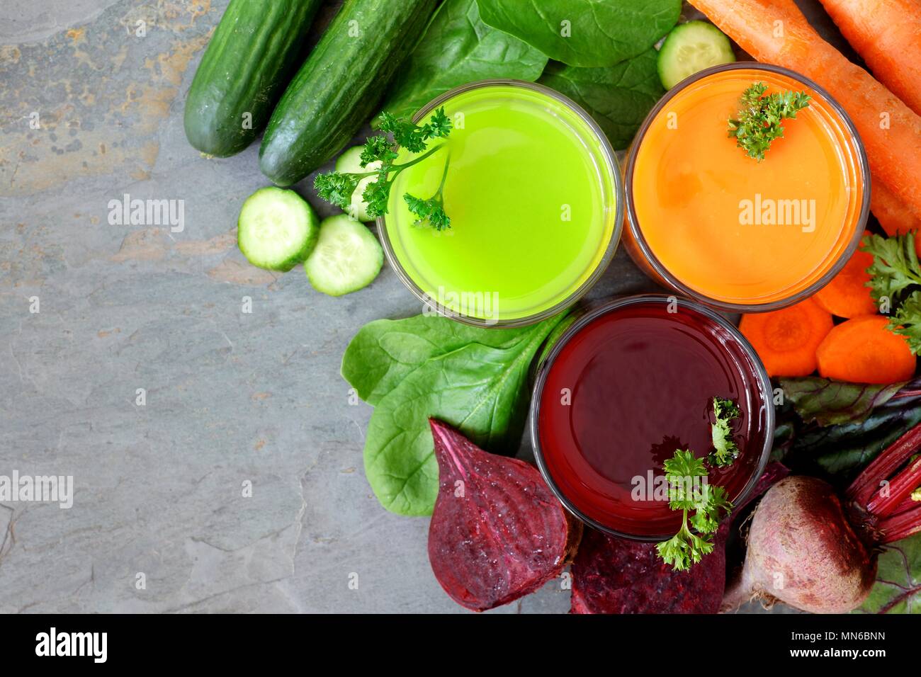 Three glasses of healthy vegetable juice with scattered ingredients ...