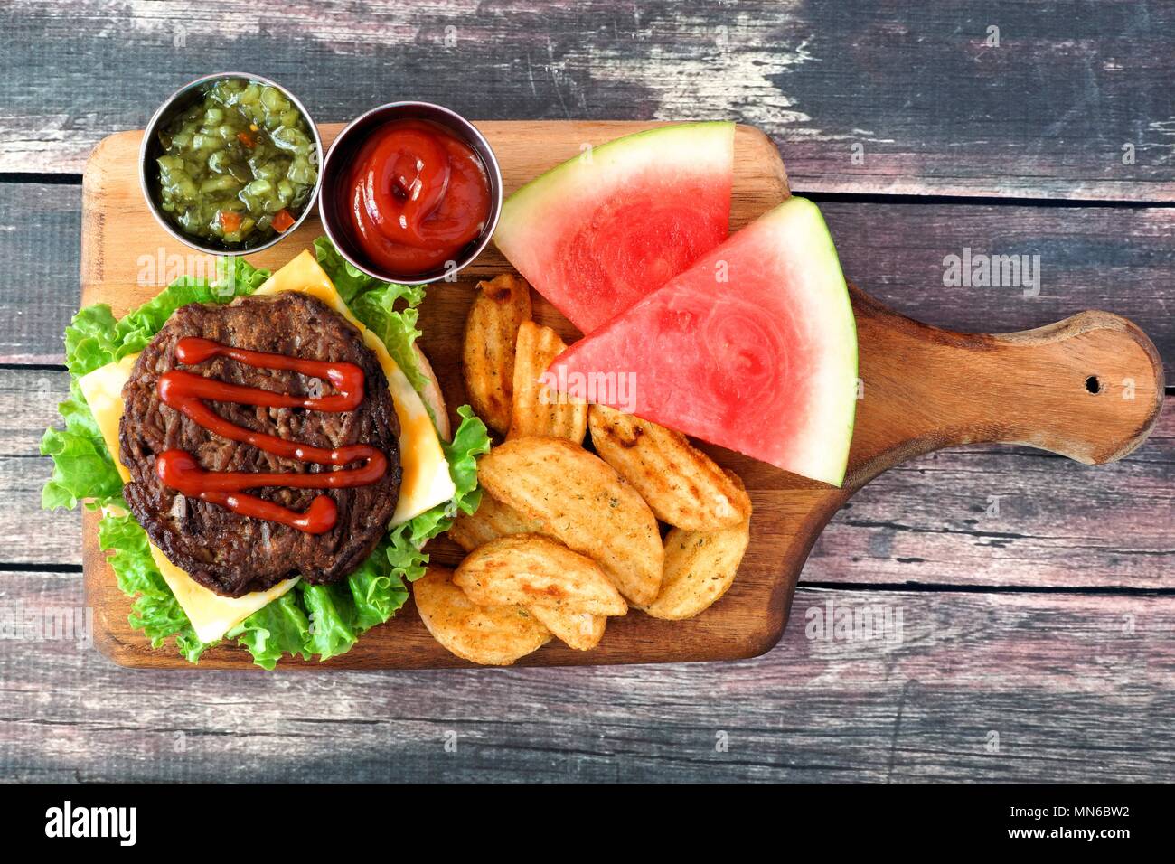 Picnic scene with open hamburger, potato wedges and watermelon on a ...
