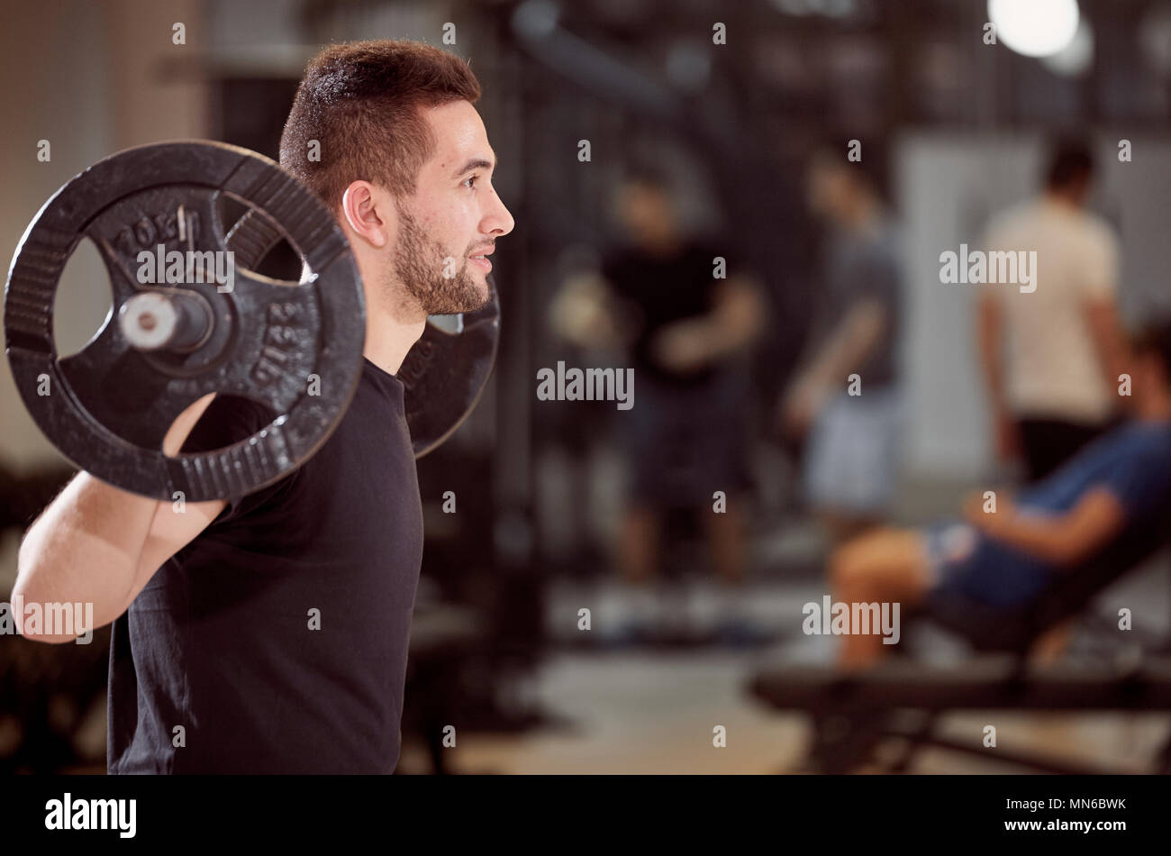 upper body shot, squat exercise close up, young man holding barbell ...
