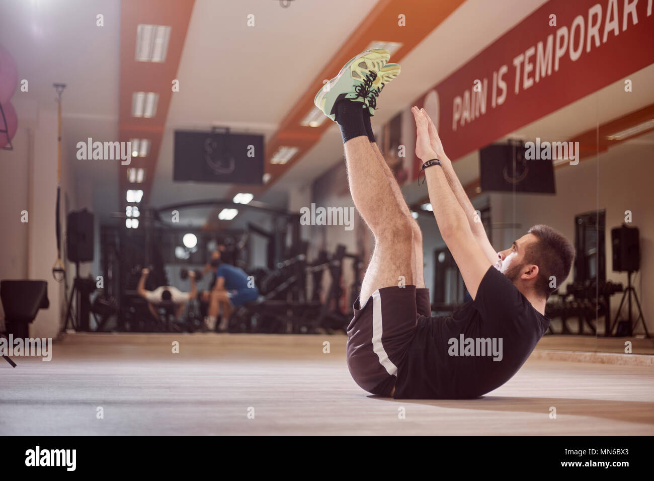 one young man, ordinary average man, exercise abs, arms extended high ...