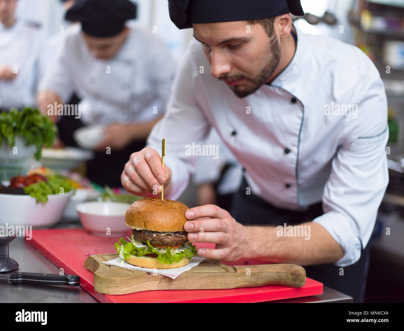 master chef putting toothpick on a burger in restaurant kitchen Stock ...