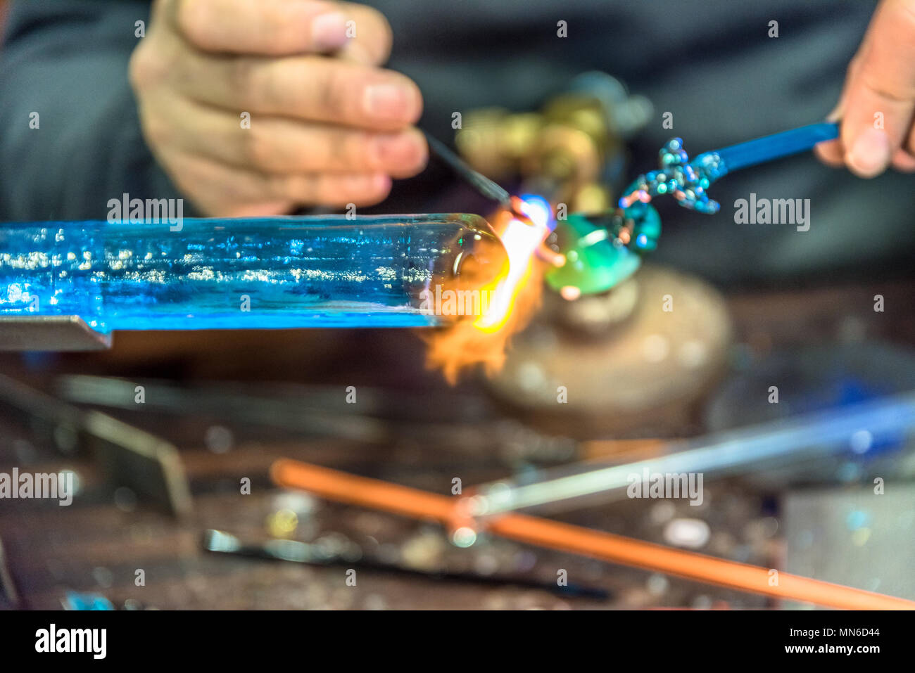 Hands of the handicrafts man making a glass subject at fair of crafts ...