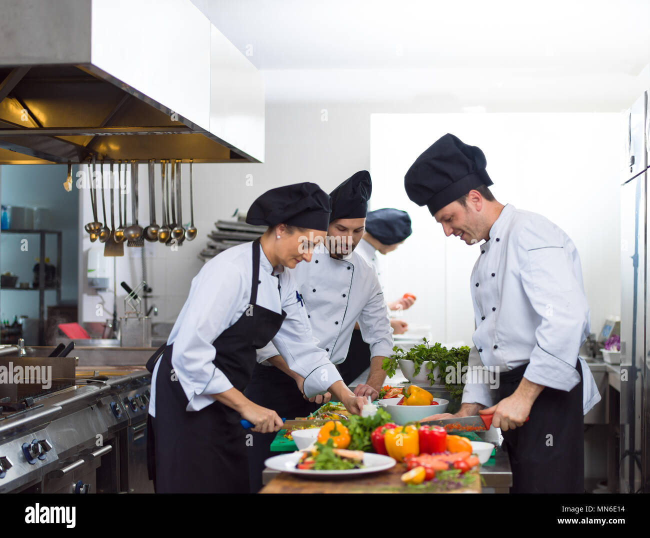 Professional team cooks and chefs preparing meals at busy hotel or ...
