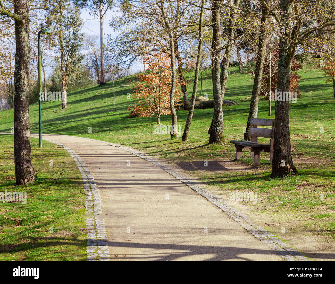 Garden or park bench near an empty dirt path, track, trail or pathway ...