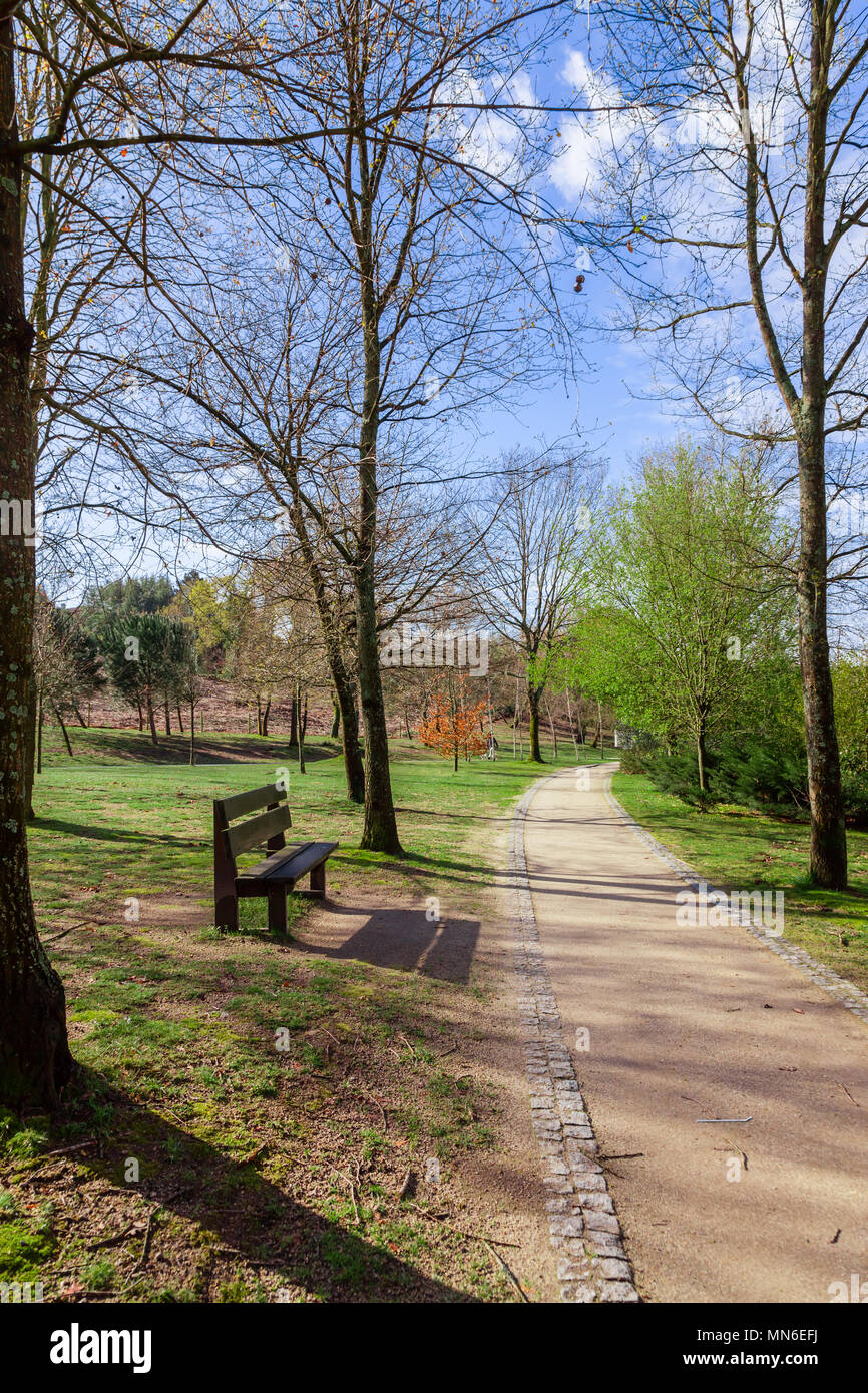 Garden or park bench near an empty dirt path, track, trail or pathway ...