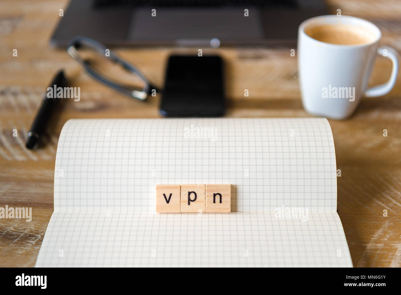 Closeup on notebook over wood table background, focus on wooden blocks with letters making VPN ...