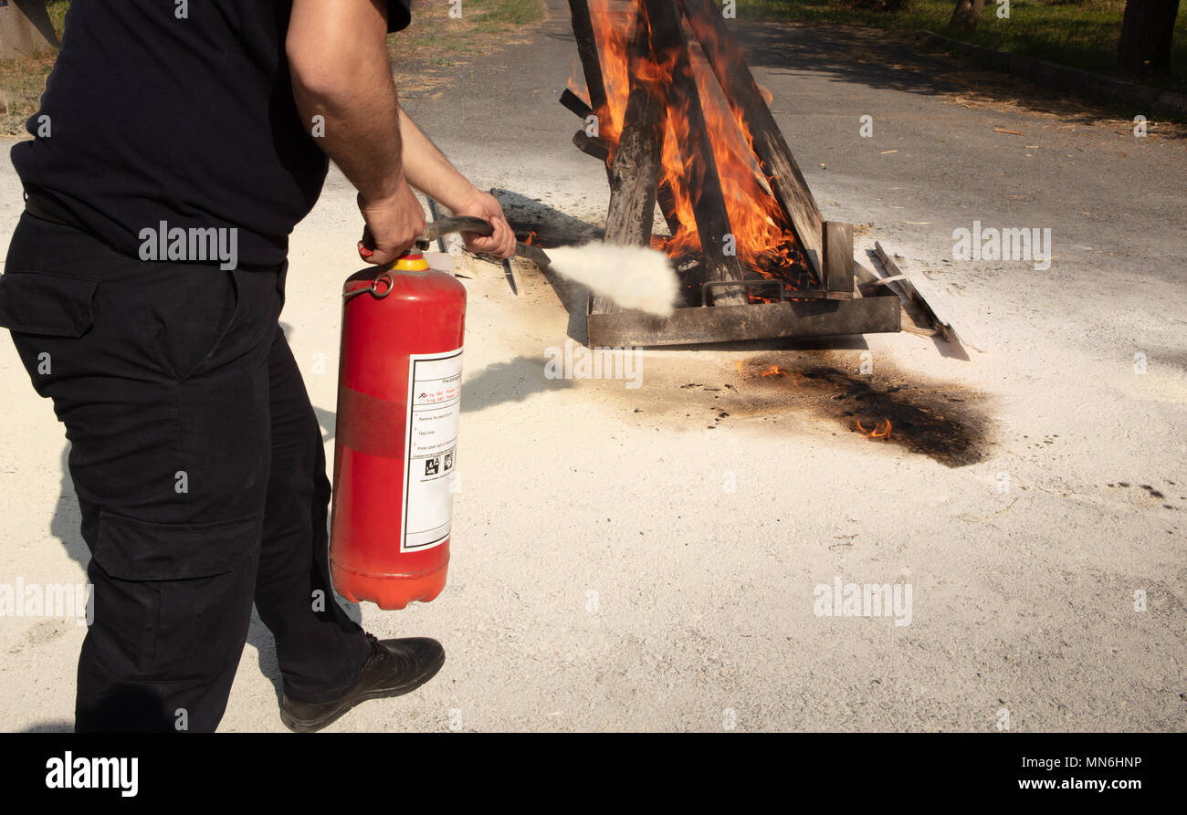 Young man pointing a powder type fire extinguisher forwards towards the ...