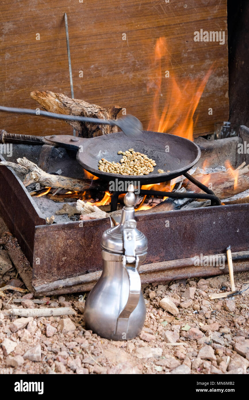 Coffee beans being rosted on fire next to a traditional bedouin coffee ...