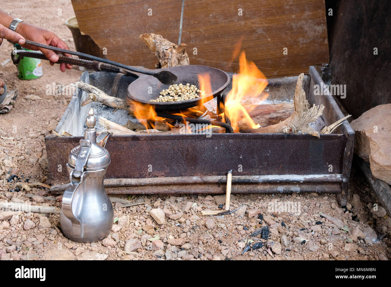Coffee beans being rosted on fire next to a traditional bedouin coffee ...
