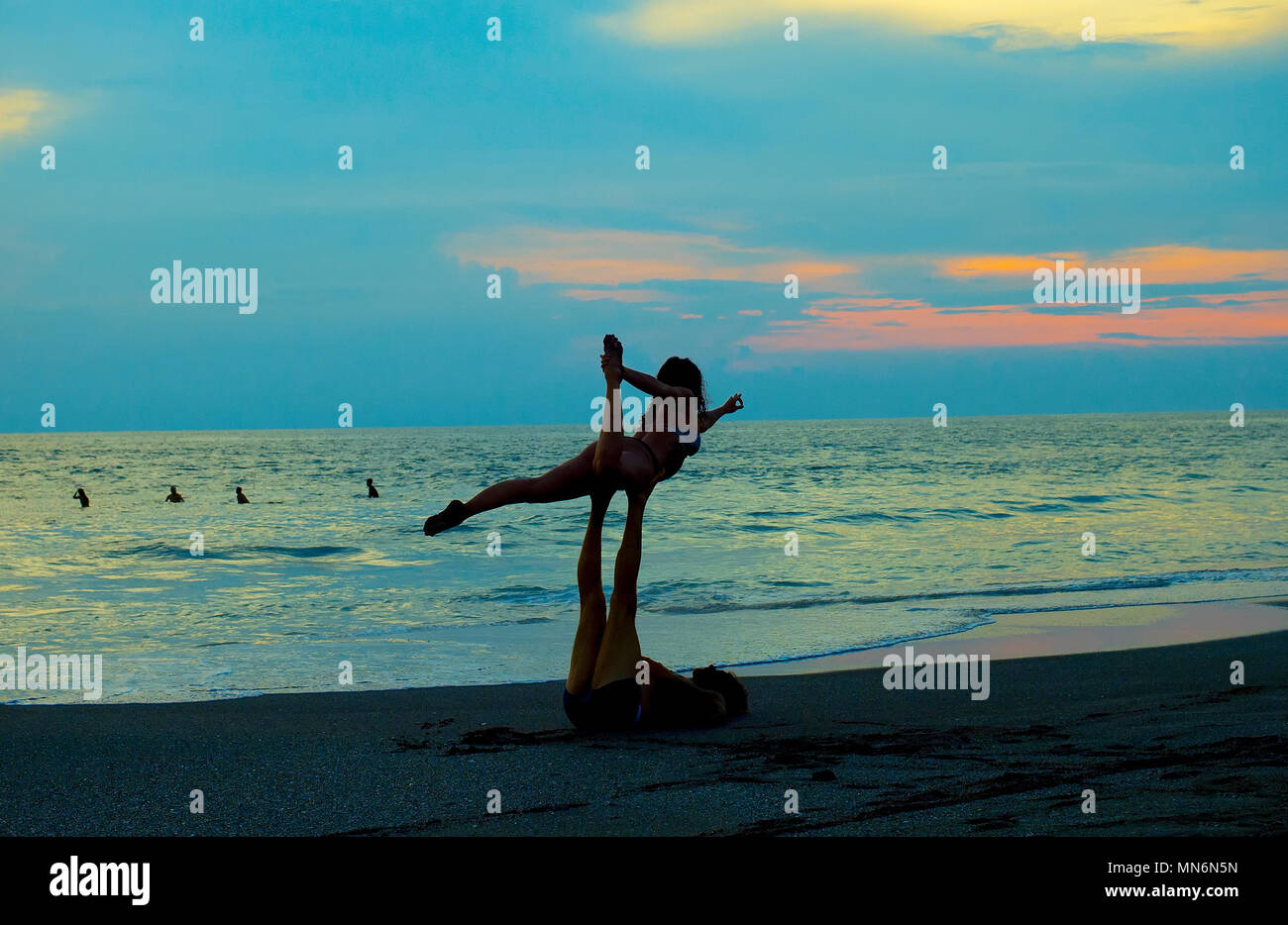 Couple practice yoga on the beach at sunset Stock Photo - Alamy