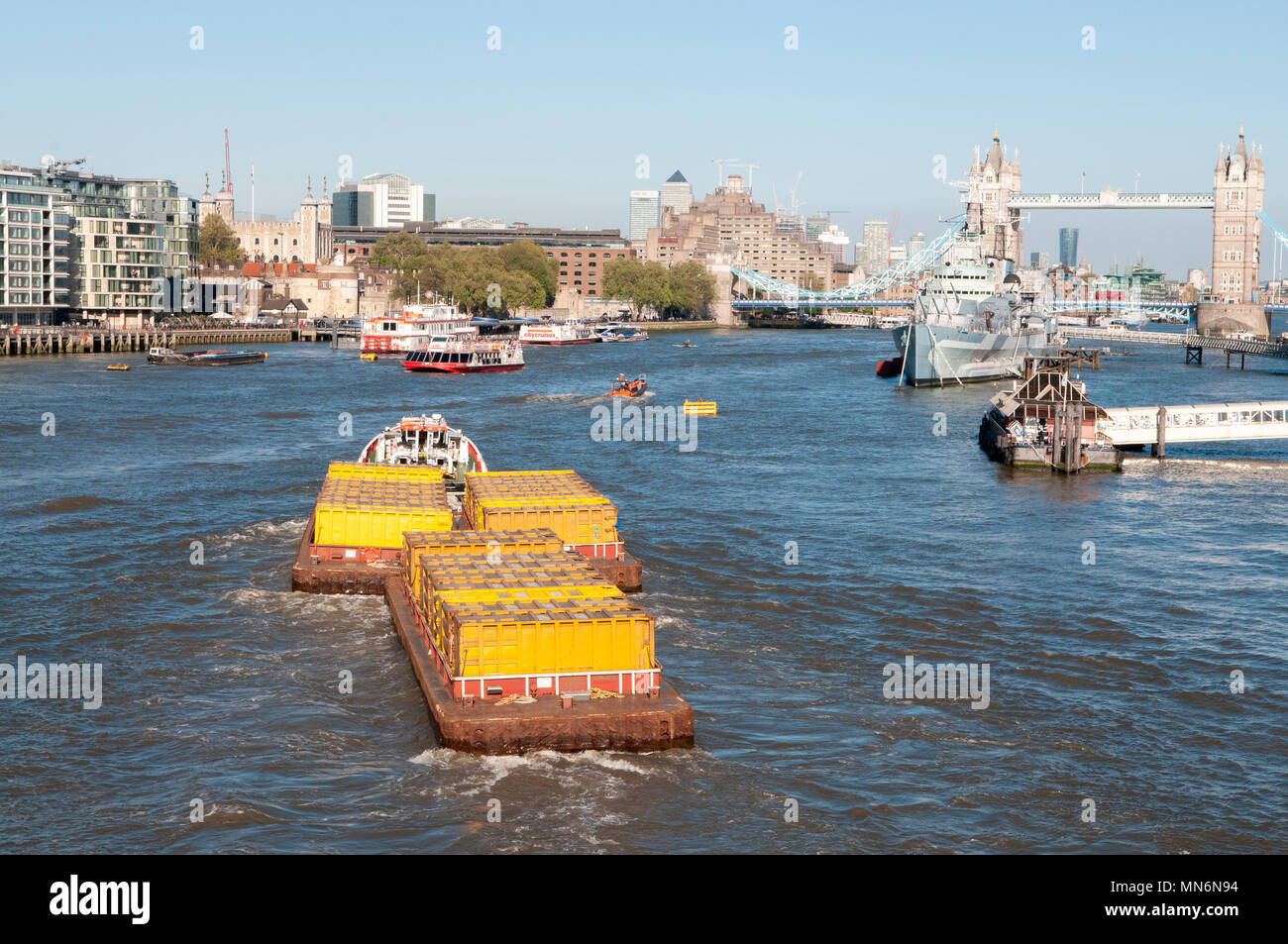 Tug tows barges holding yellow shipping containers filled with general ...