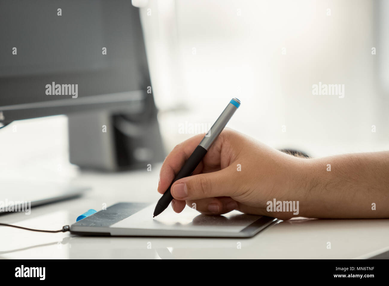 Closeup image of young man working with stylus and graphic tablet at ...