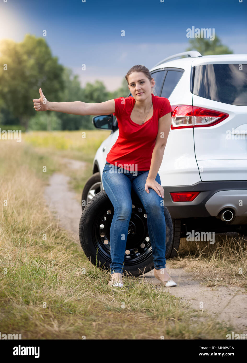Upset young woman with broken car on deserted road hitch-hiking and ...