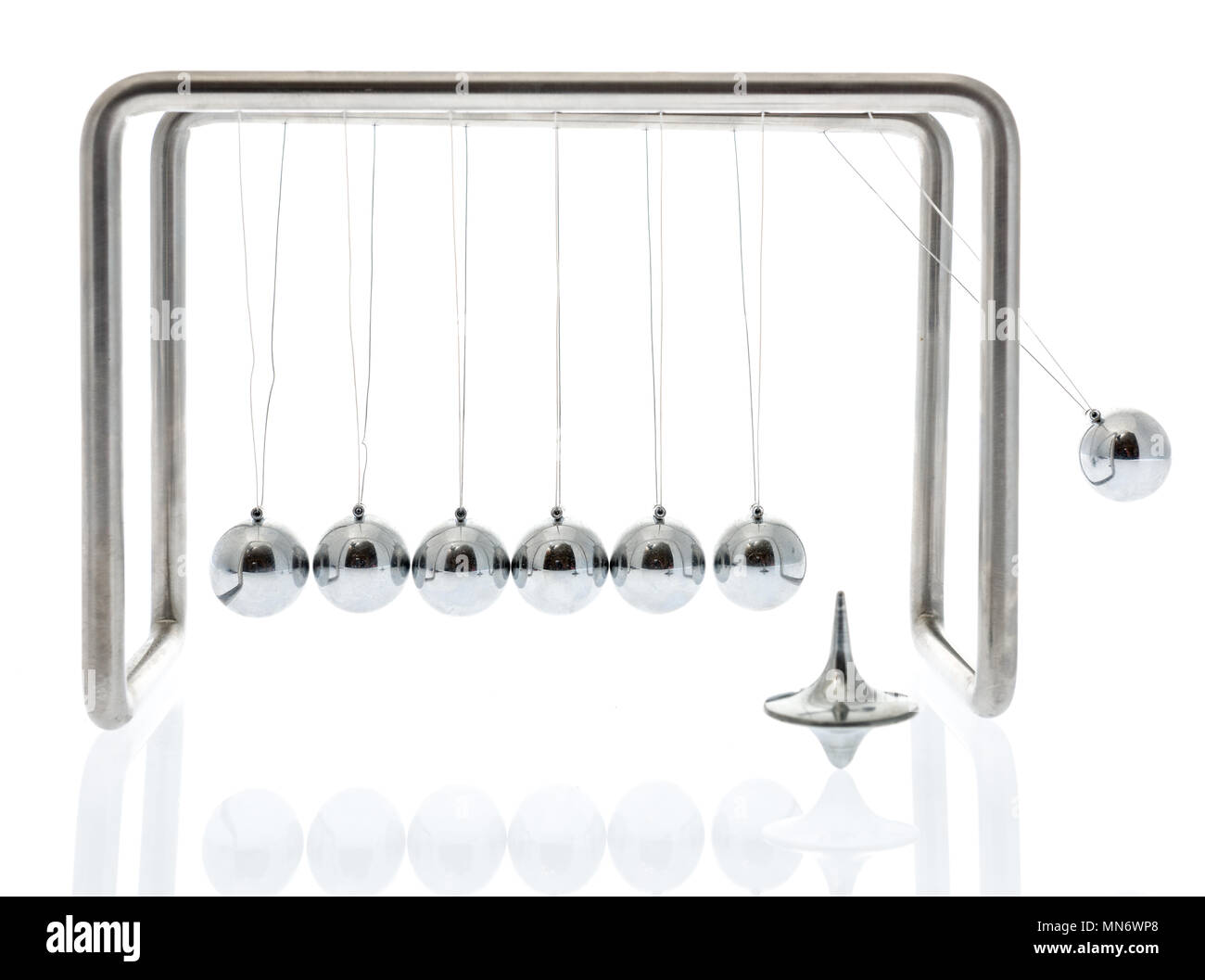 Physics at work with a Newton cradle swinging and a spinning top on an ...
