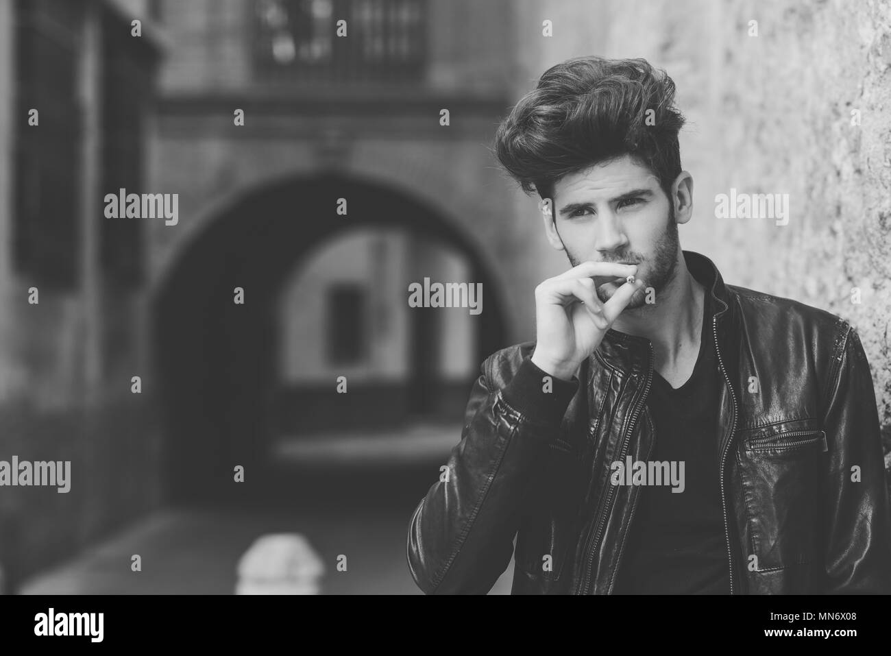 Portrait of young man smoking a cigarette in urban background Stock ...