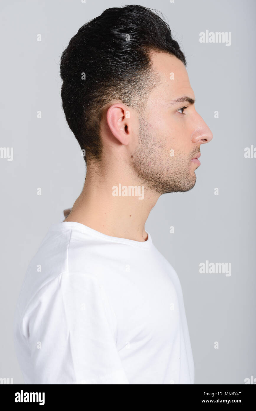 Portrait of a smart serious young man standing against white background ...