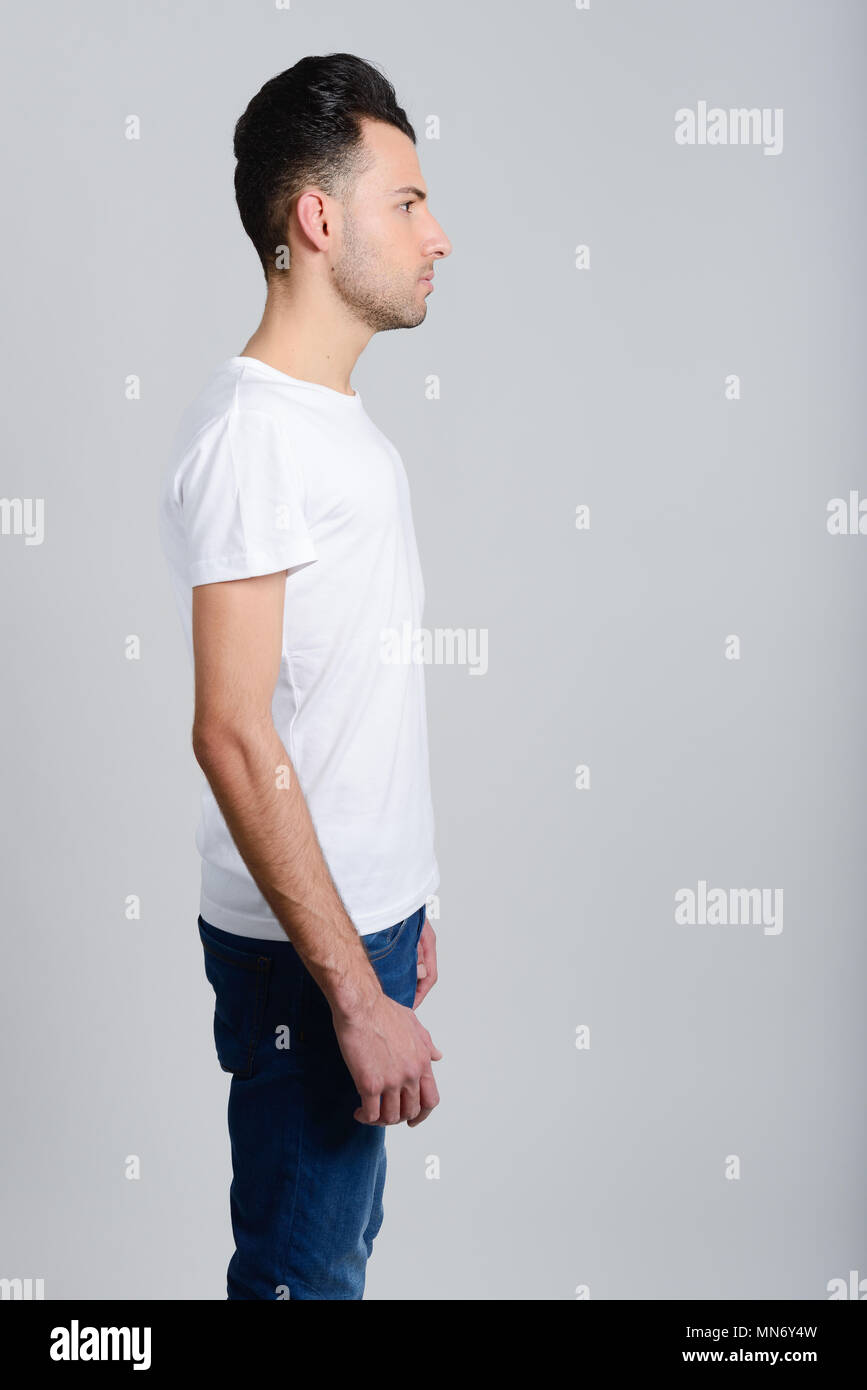Portrait of a smart serious young man standing against white background ...