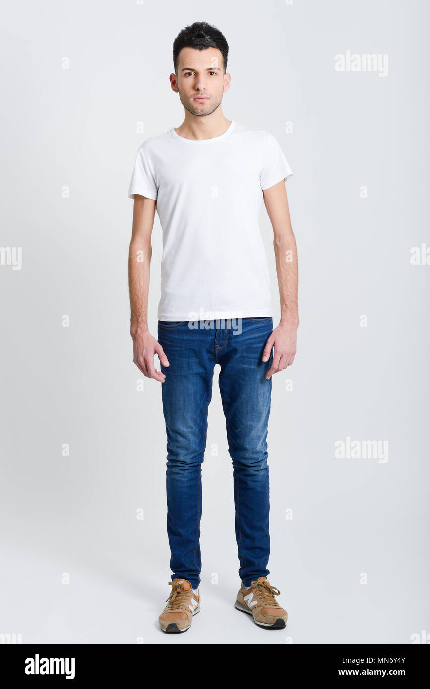 Portrait of a smart serious young man standing against white background ...