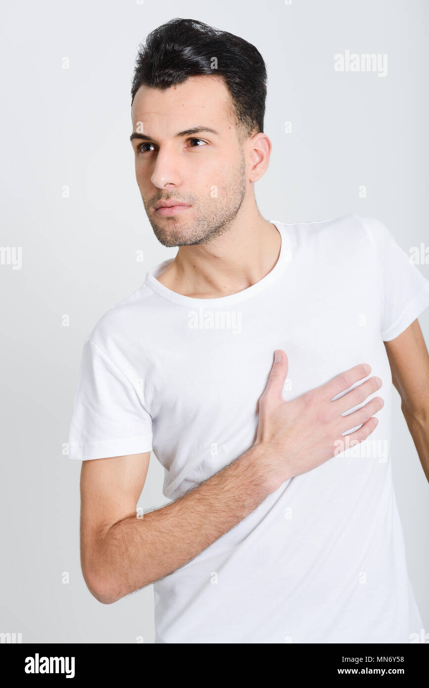 Portrait of a smart serious young man standing against white background ...