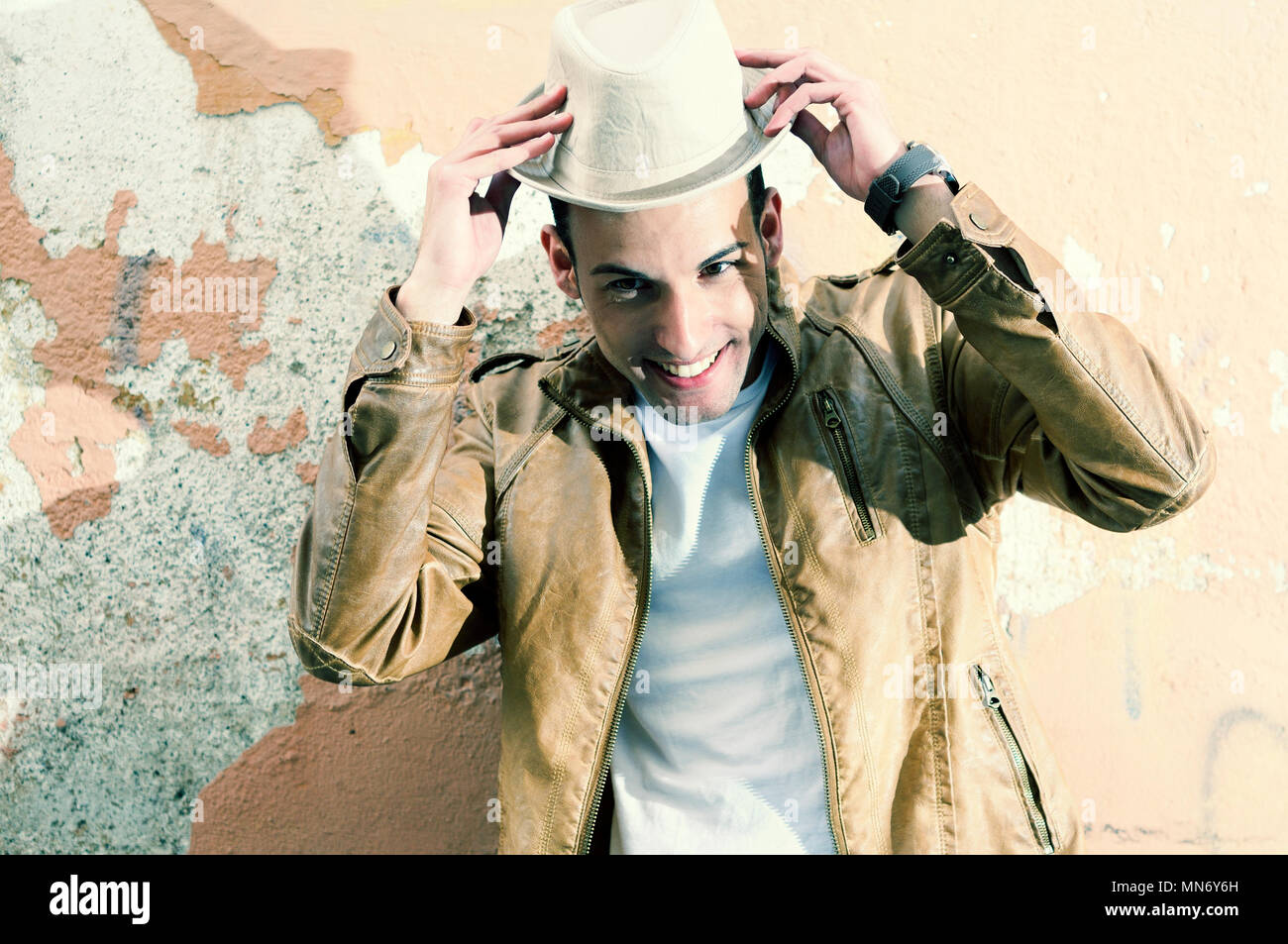 Portrait of a handsome young man smiling with a hat in urban background ...