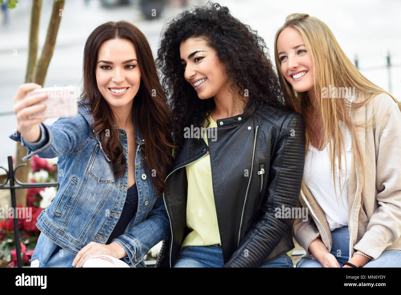 Group of multi-ethnic young women taking a selfie photograph together ...