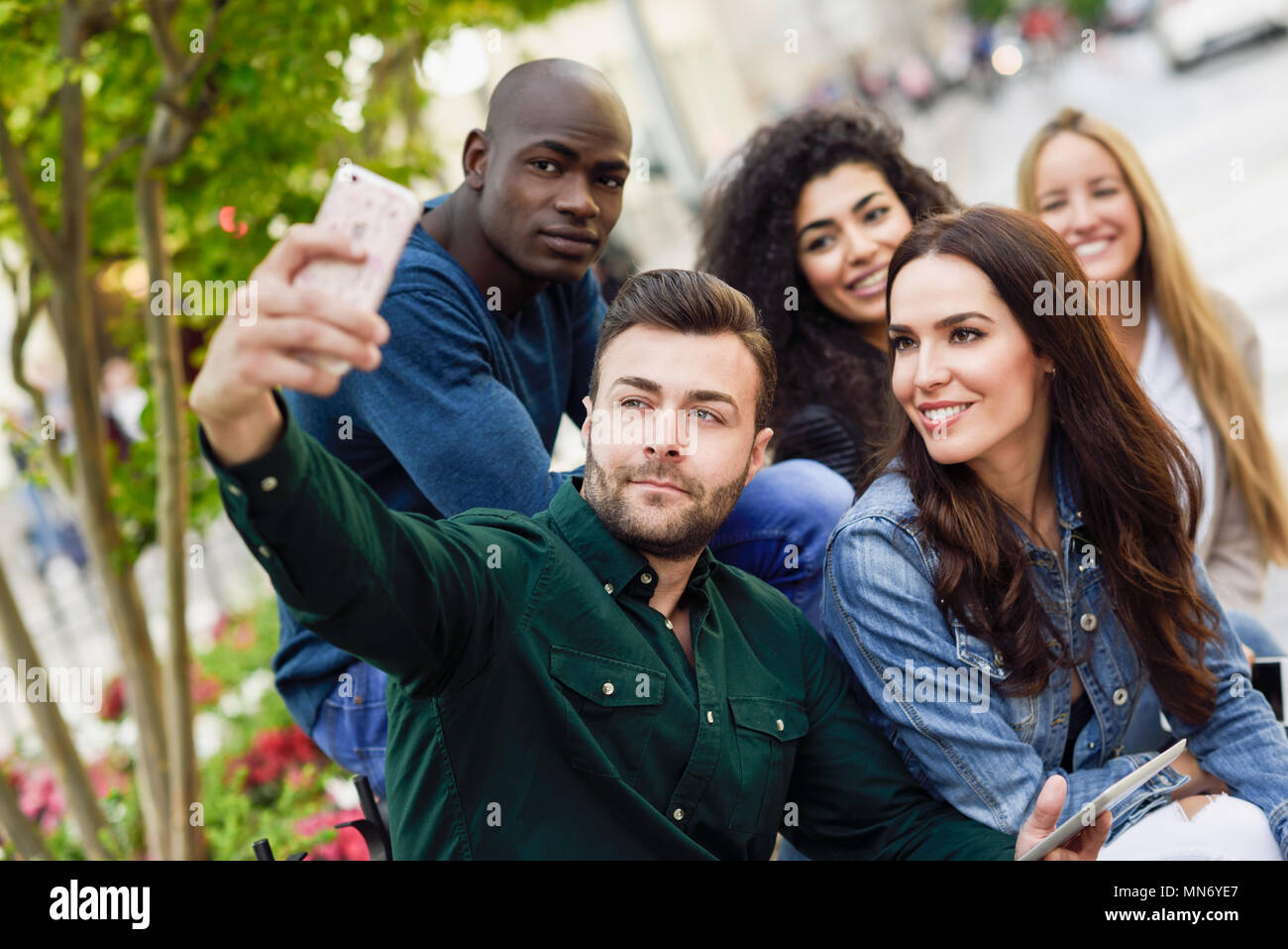 Multi-ethnic group of young people taking selfie photograph together outdoors. Beautiful funny ...