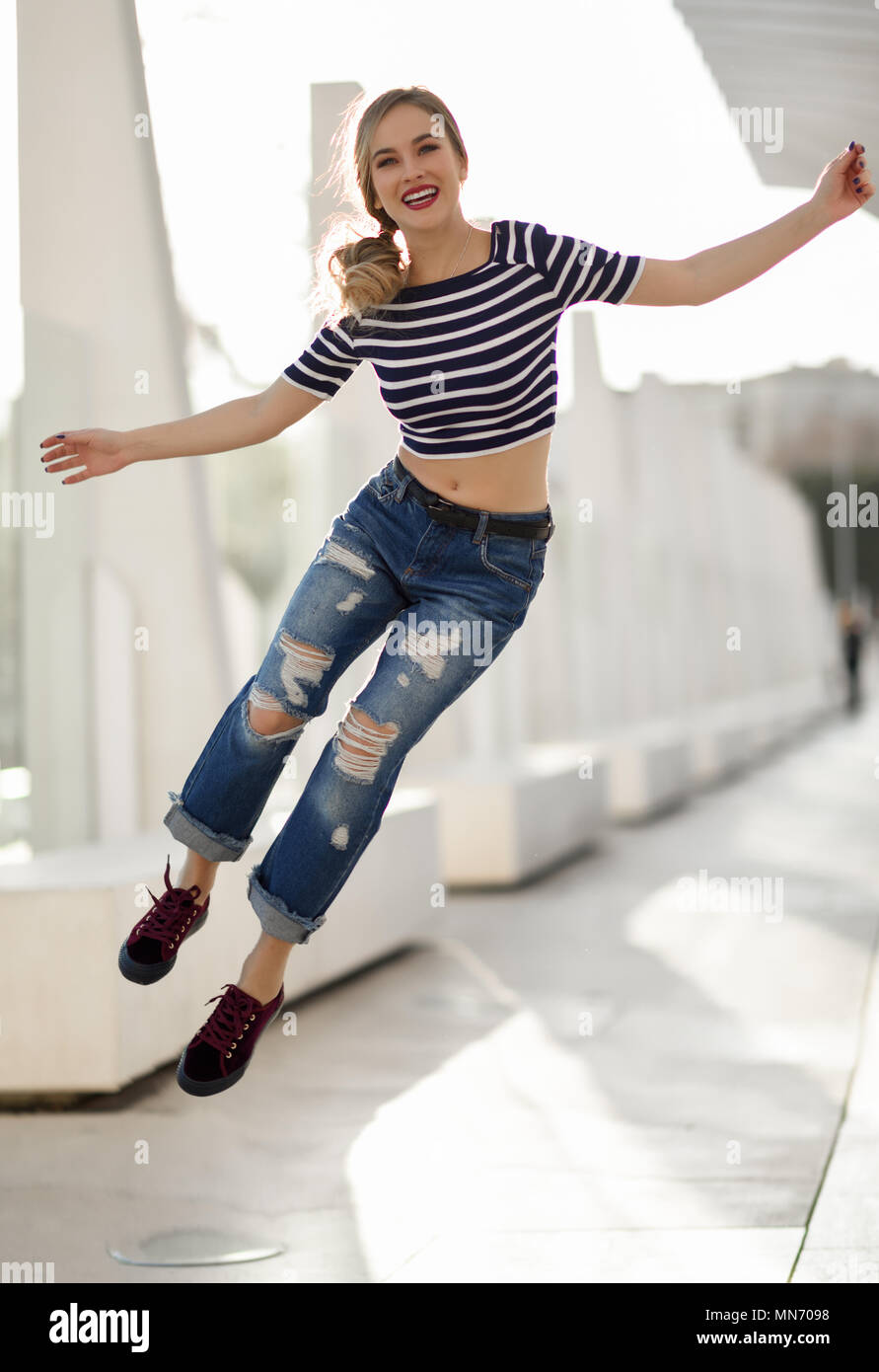 Funny blonde woman jumping in urban background. Beautiful young girl ...