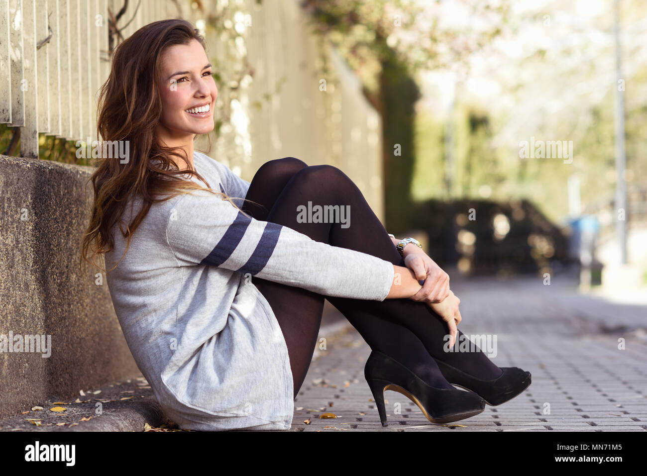 Portrait of funny female model of fashion with high heels sitting on ...