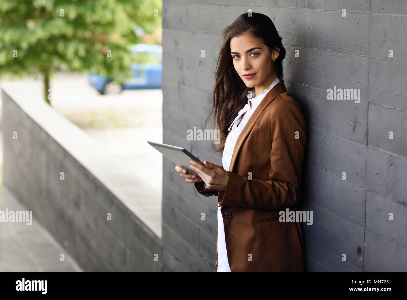Young businesswoman with tablet computer standing outside of an office ...