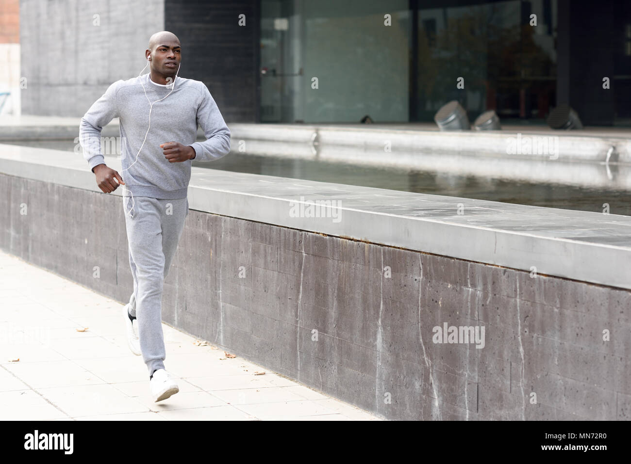 Attractive black man running in urban background. Male doing workout ...