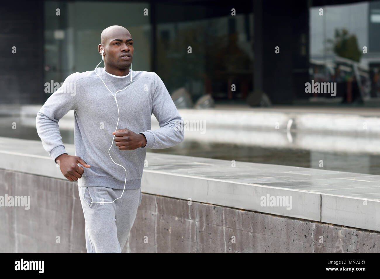 Attractive black man running in urban background. Male doing workout ...