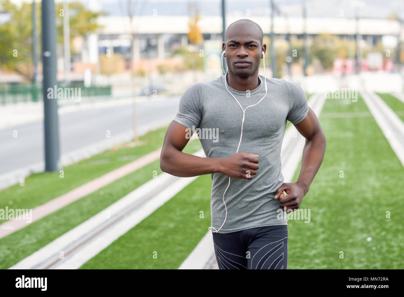 Black man running and listening to music in urban background. Handsome ...
