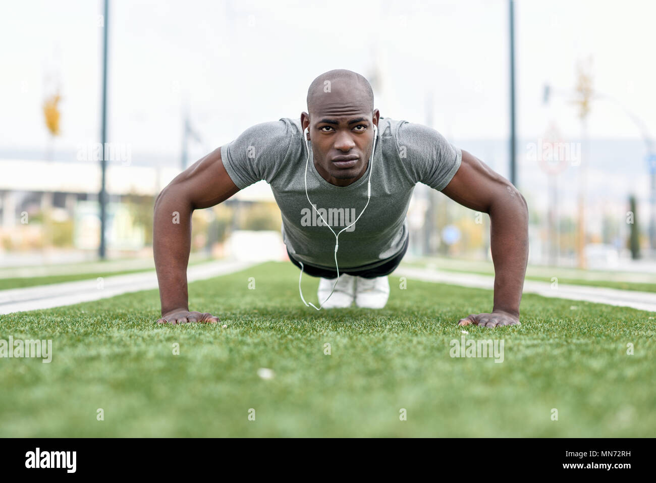 Fitness black man exercising push ups listening to music with ...