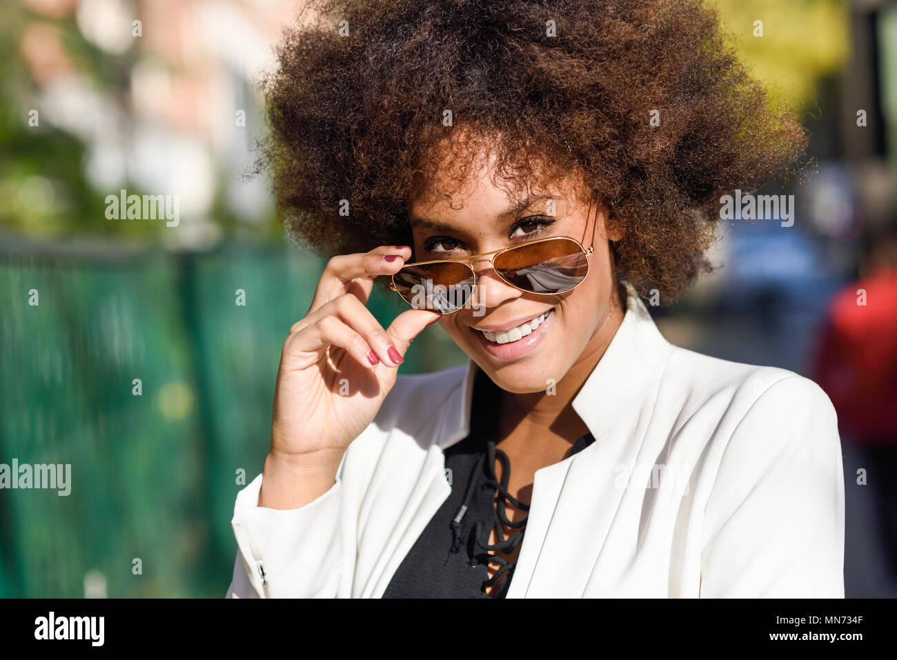 Young black woman with afro hairstyle standing in urban background with ...
