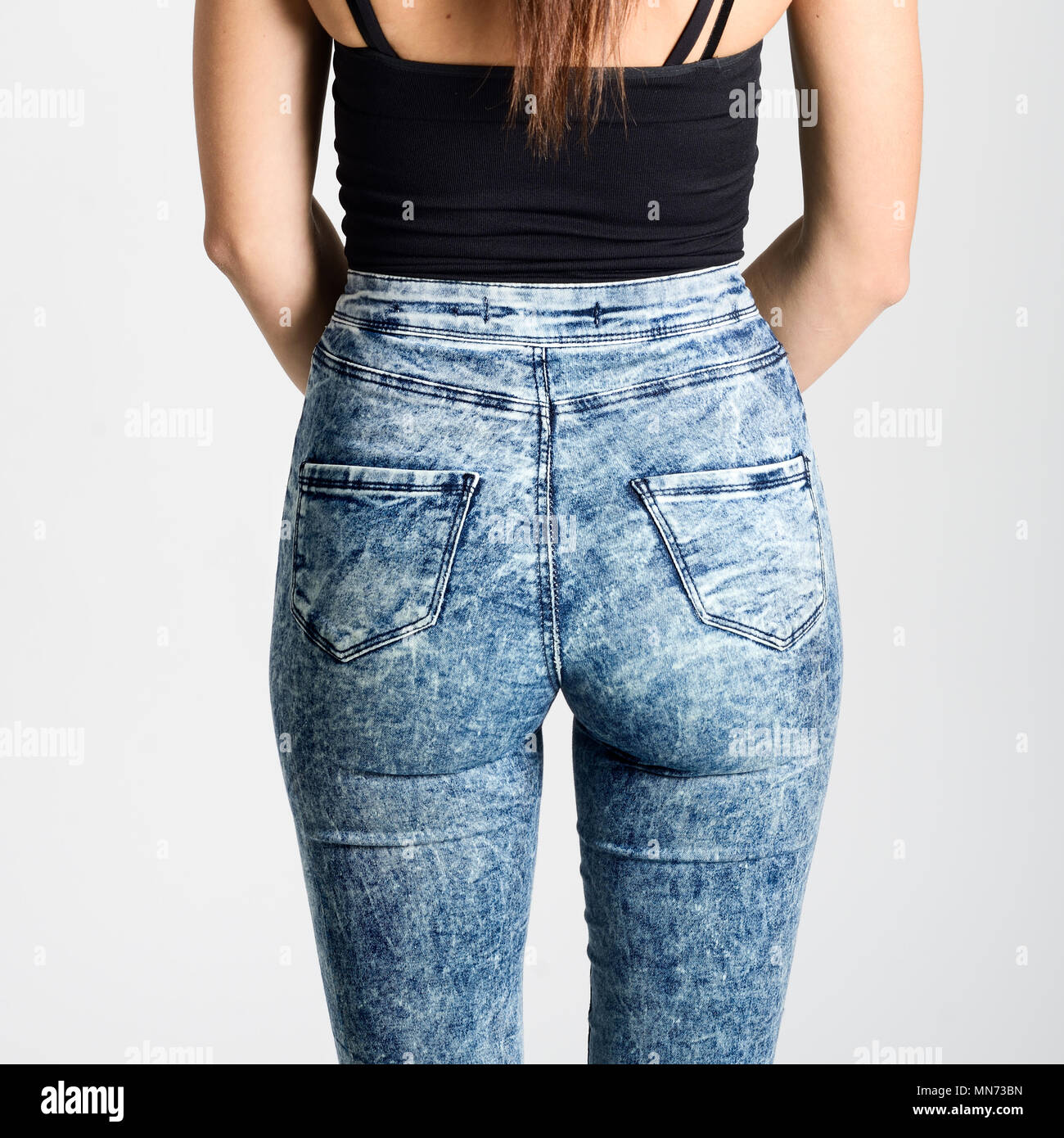 Back side of woman wearing high-waisted jeans. Studio shot. Girl with ...