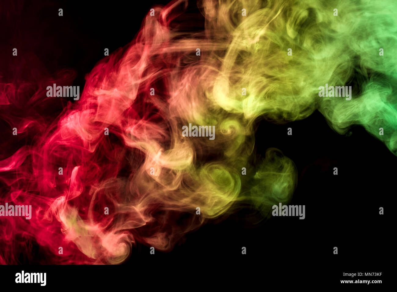 Thick red, yellow and green colorful smoke on a black isolated ...