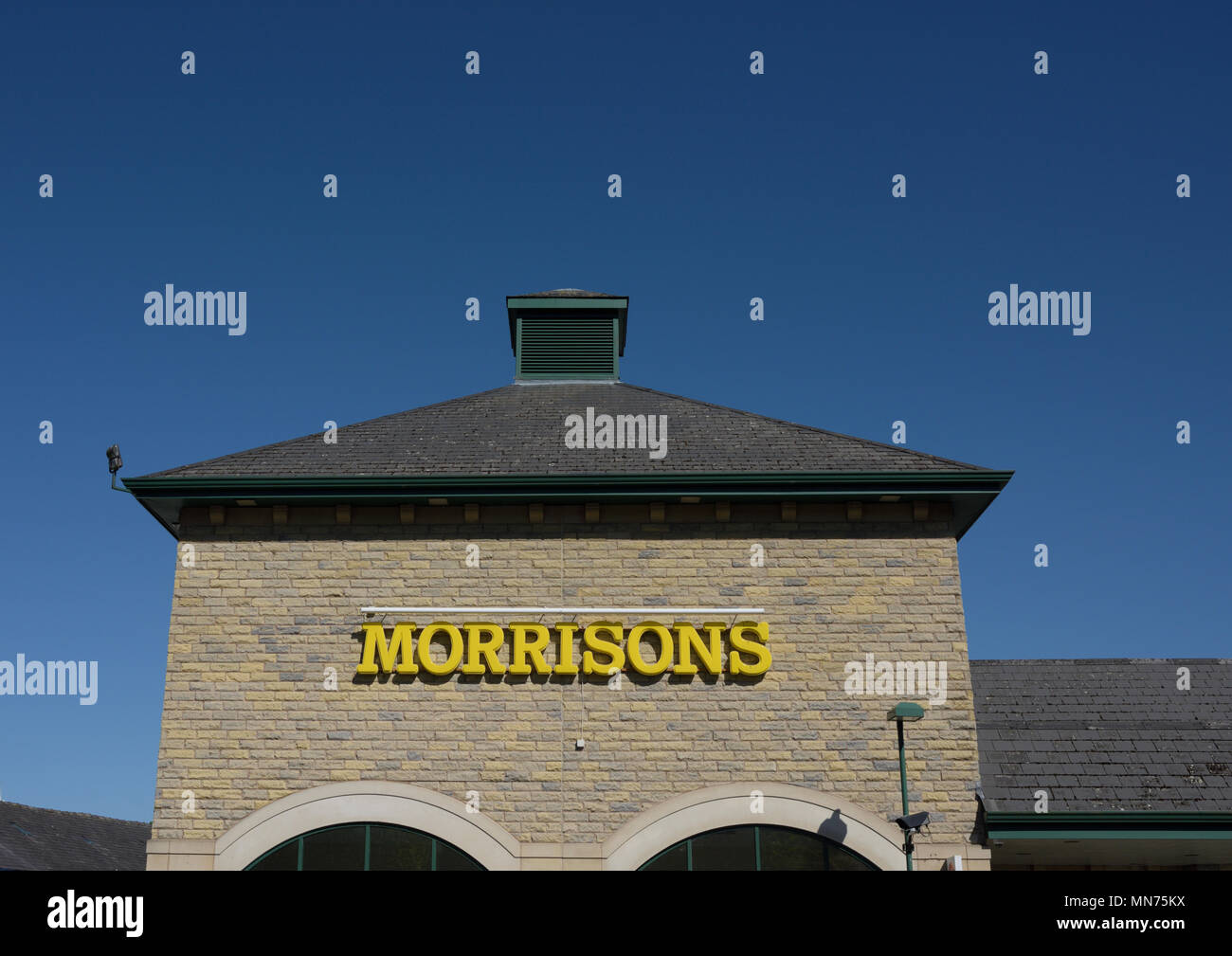 Morrisons supermarket with stone wall and slate roof with clear blue ...