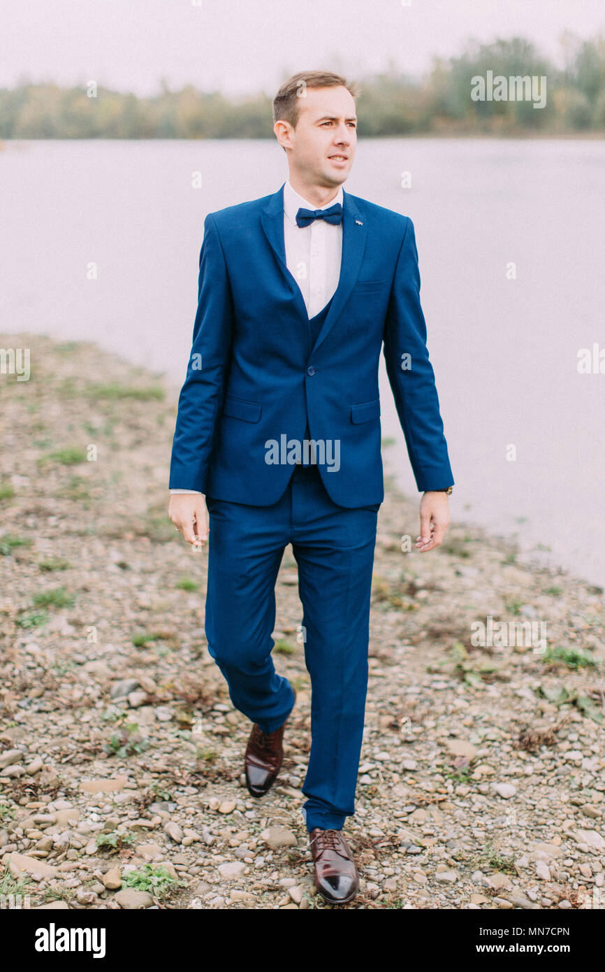Full-length photo of the groom looking aside during the walk along the ...