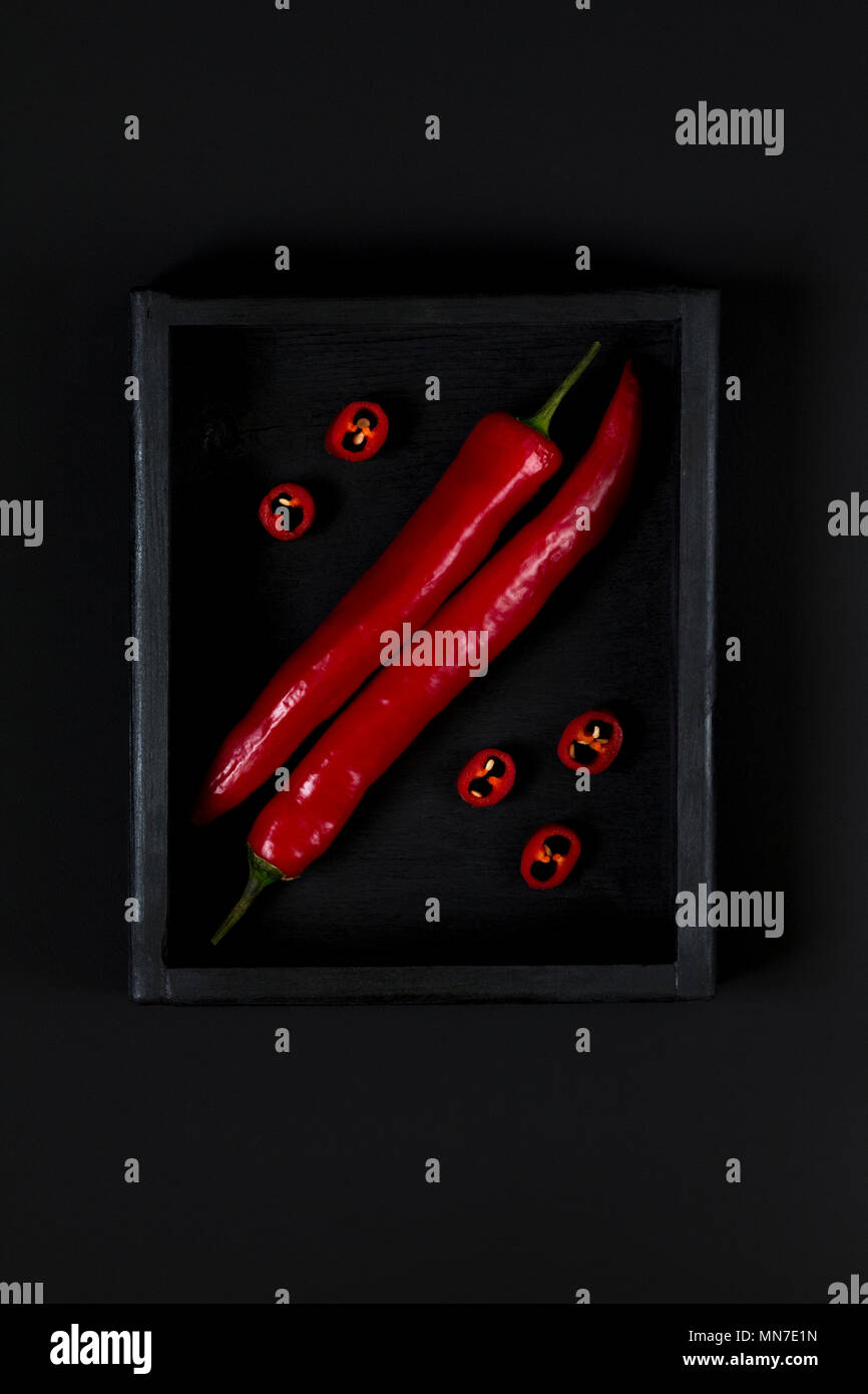 Chili pepper in a wooden box on a black background. Black and red ...