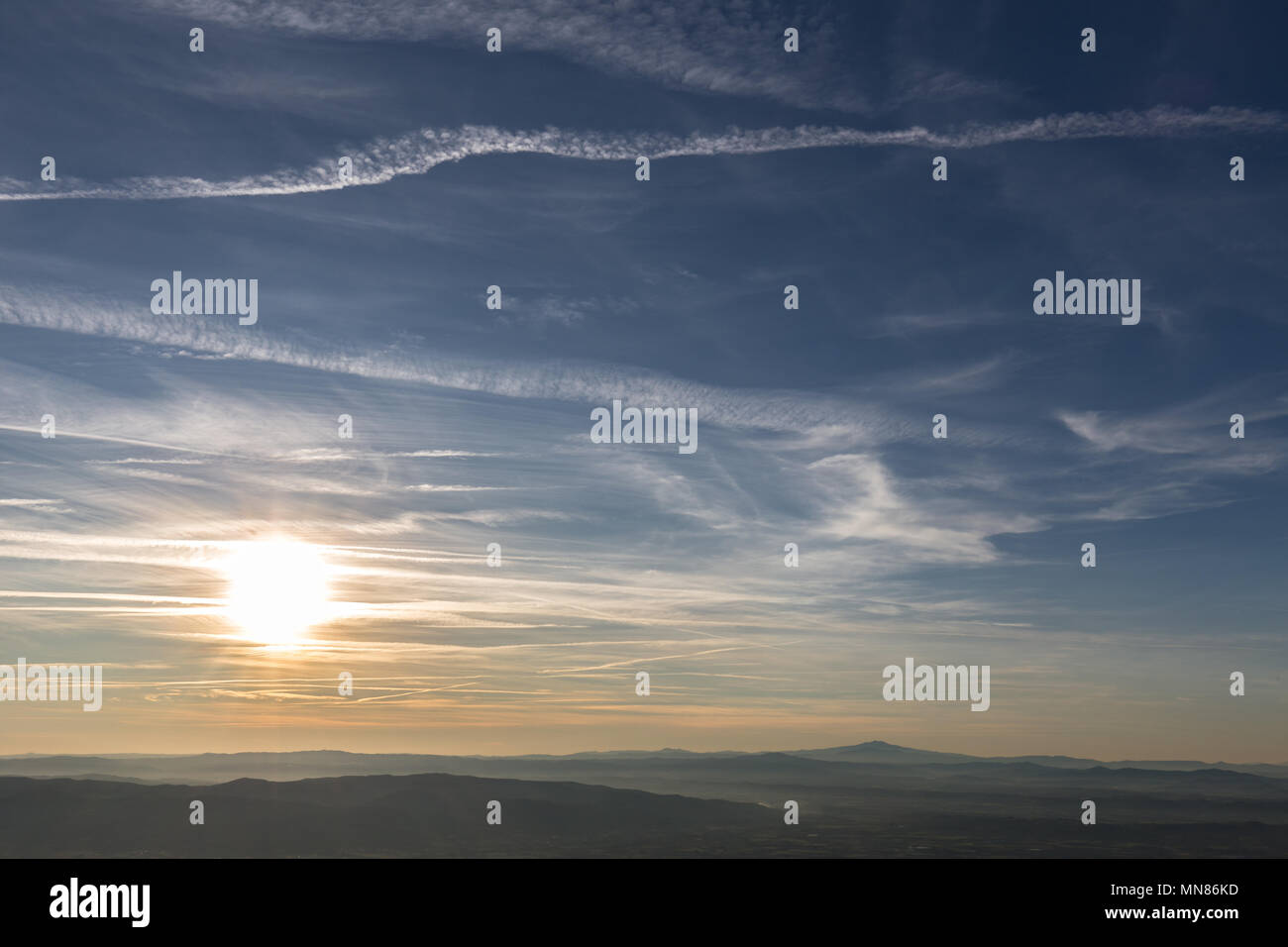 Sunset over distant mountains, with blue sky full of white clouds and ...