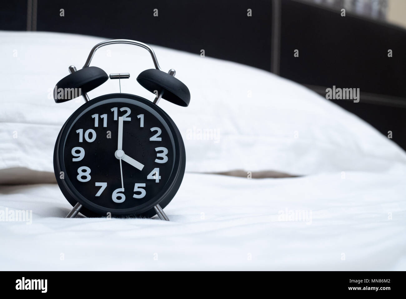Vintage alarm clock on the bed in bedroom at home, wake up or bed time ...