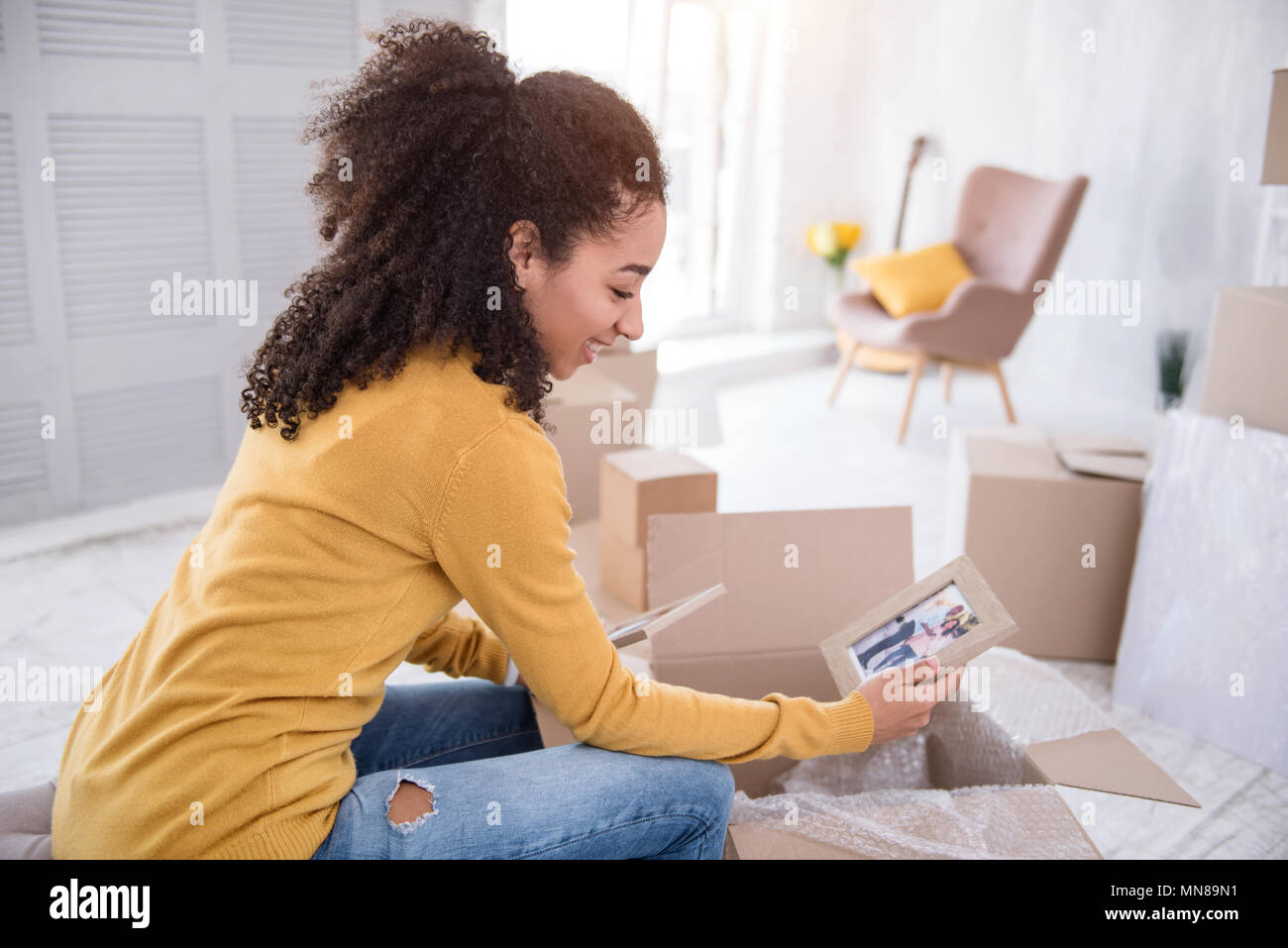 Happy girl looking at photo and smiling while packing Stock Photo - Alamy