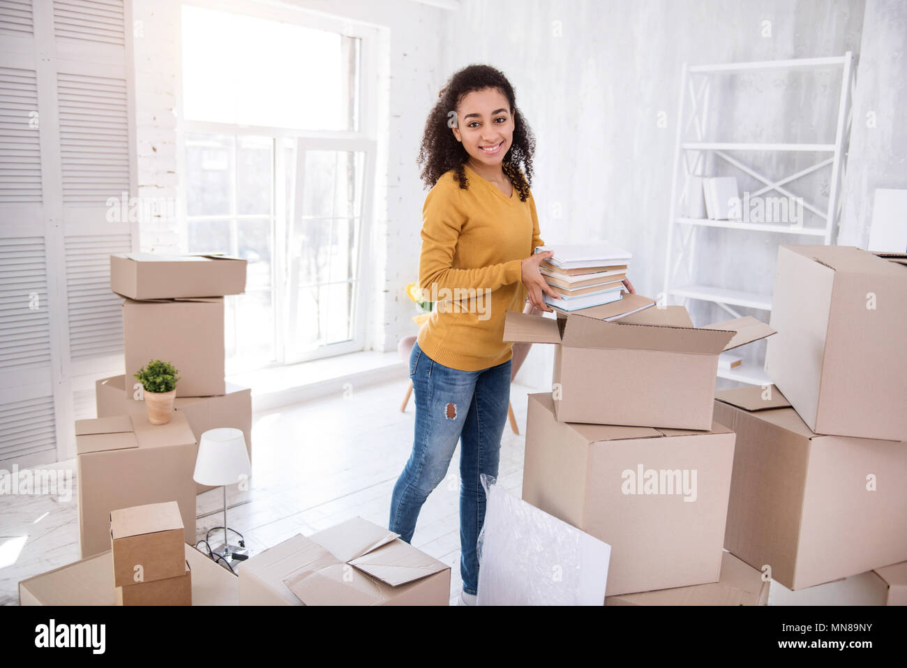 Pleasant young girl taking books out of the box Stock Photo - Alamy
