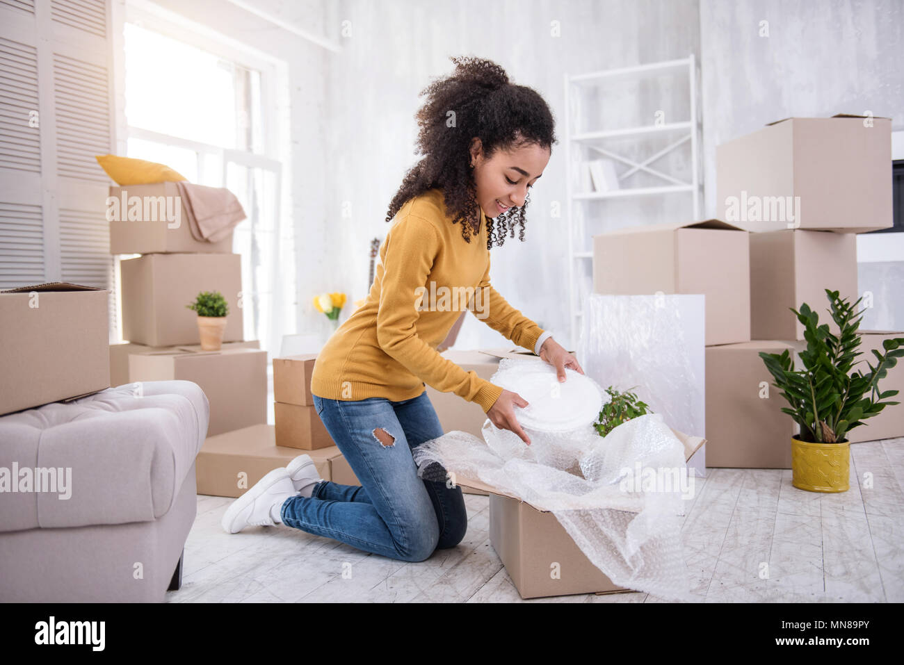 Adorable curly-haired girl unpacking plates Stock Photo - Alamy