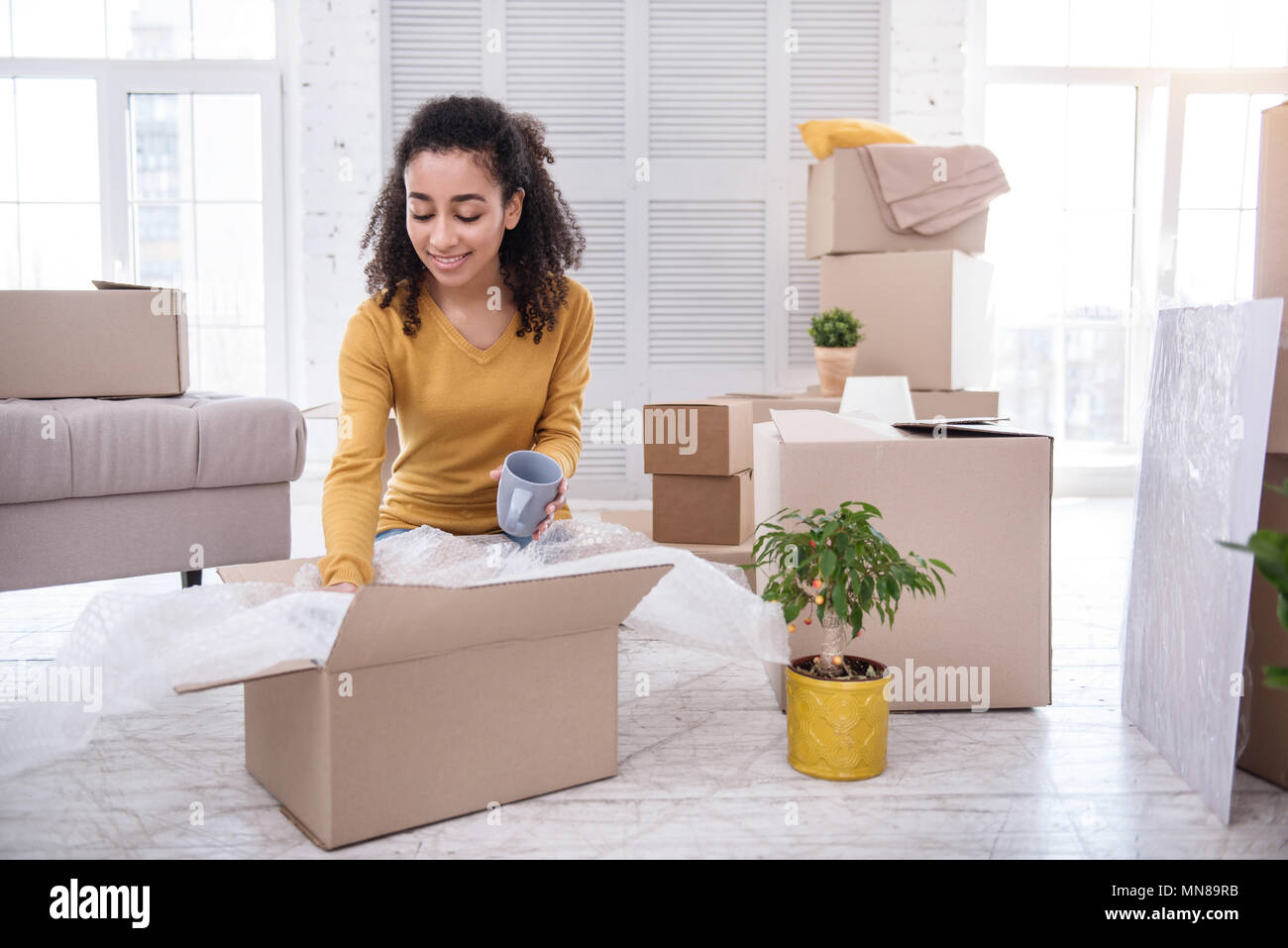 Beautiful young girl packing tea cup into box Stock Photo - Alamy